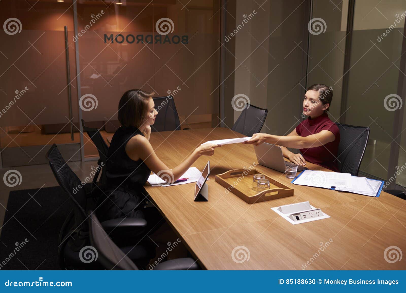 Two Businesswomen Working Late in Office Passing Documents Stock Photo ...