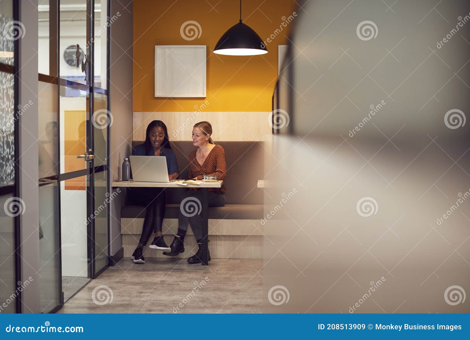 Two Businesswomen Working Late in Open Plan Office Using Laptop Stock ...