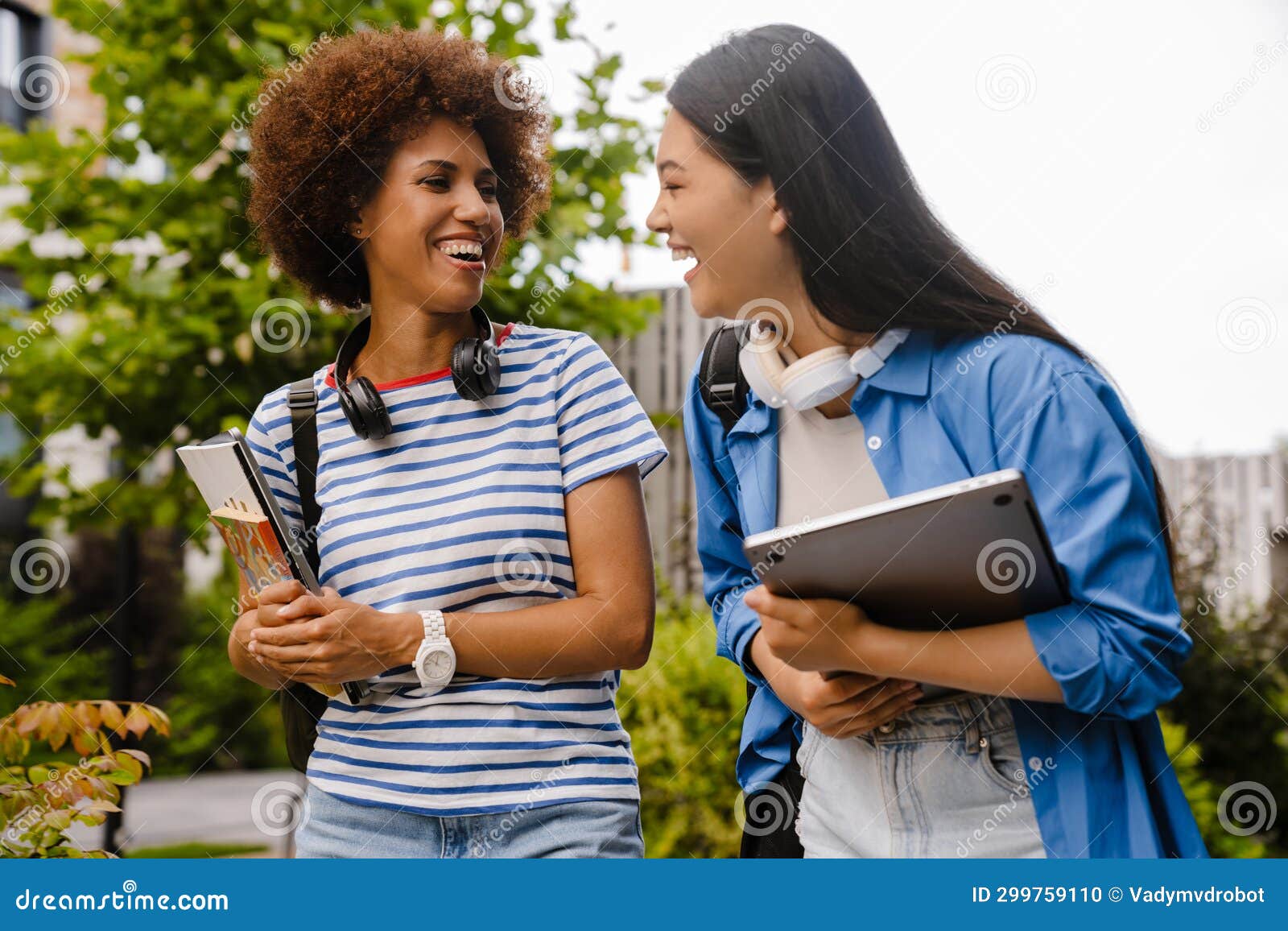 Two Cheerful Female Students Talking while Standing in University ...