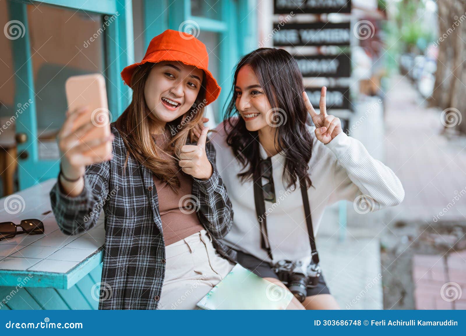 Two Cheerful Girls Take A Selfie Together Using A Cell Phone Stock