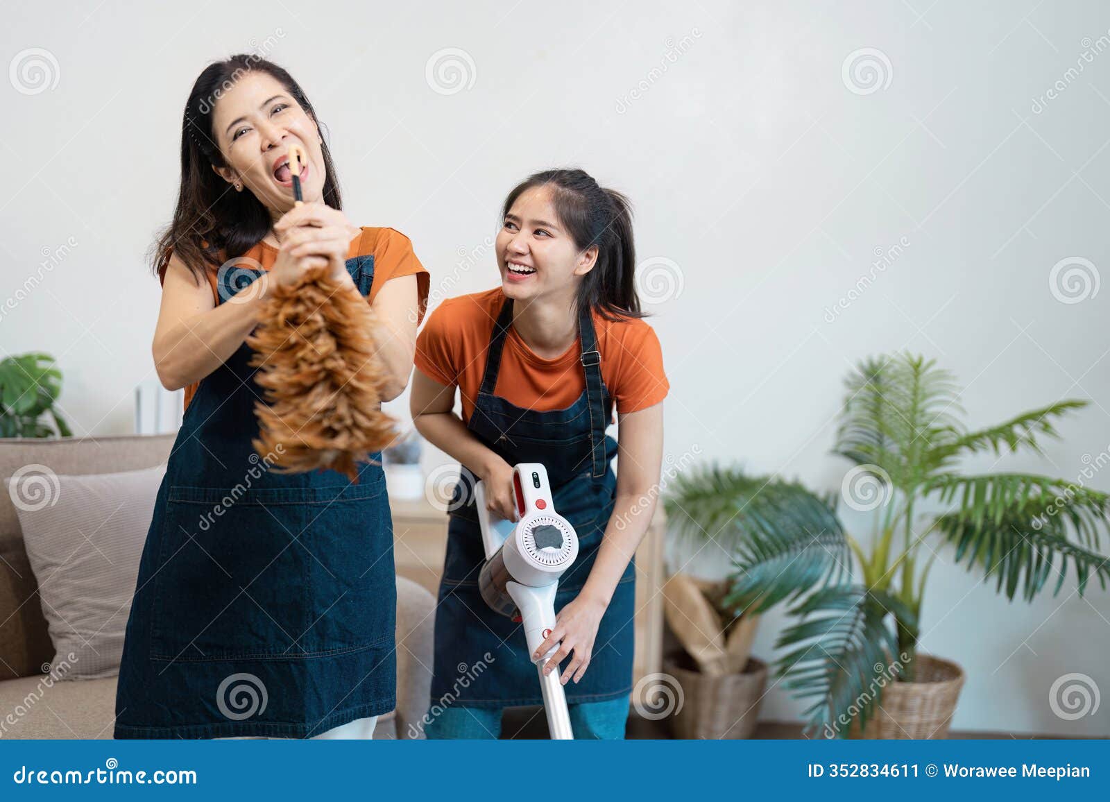 Joyful Housekeepers Engaged in Cleaning Tasks with Vacuum and Duster in ...