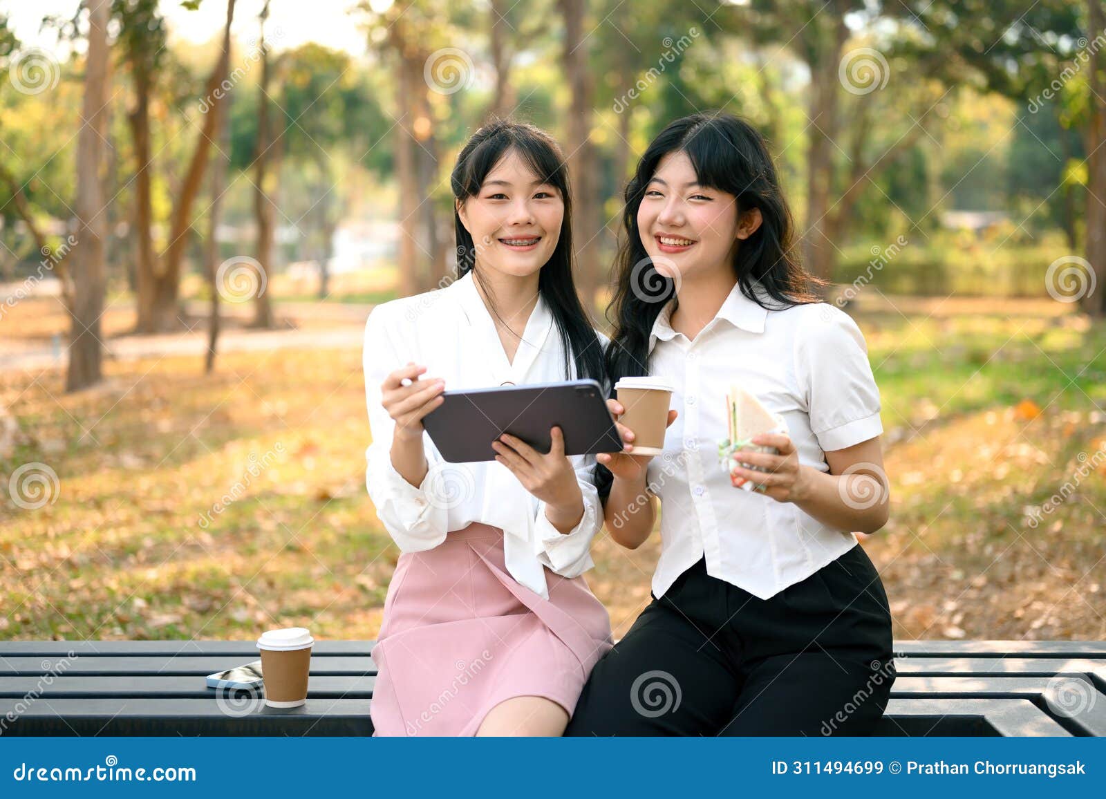 Two Cheerful Office Workers Using Digital Tablet and Chatting on a ...