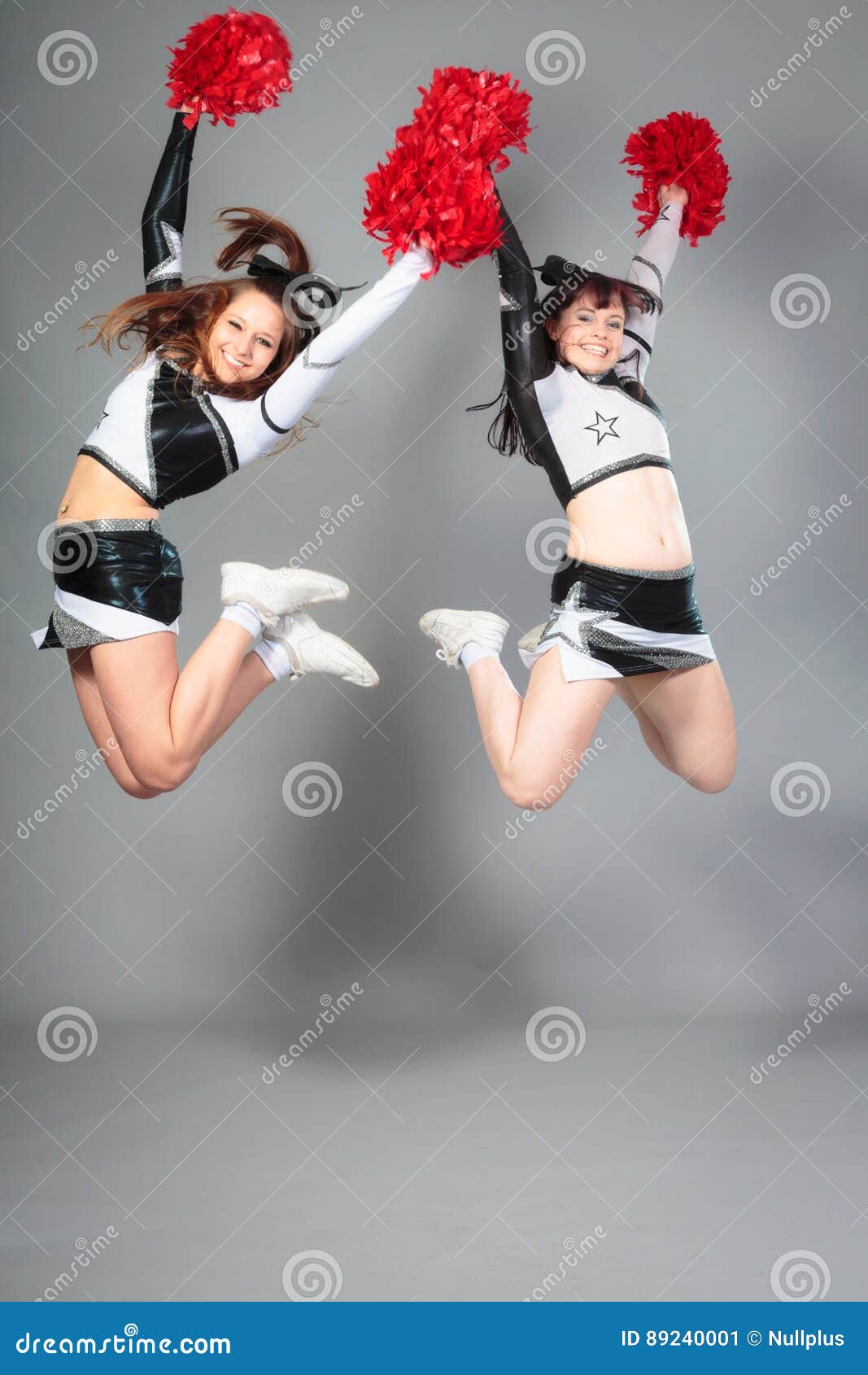Two Cheerleaders Jumping stock image. Image of stunt - 89240001