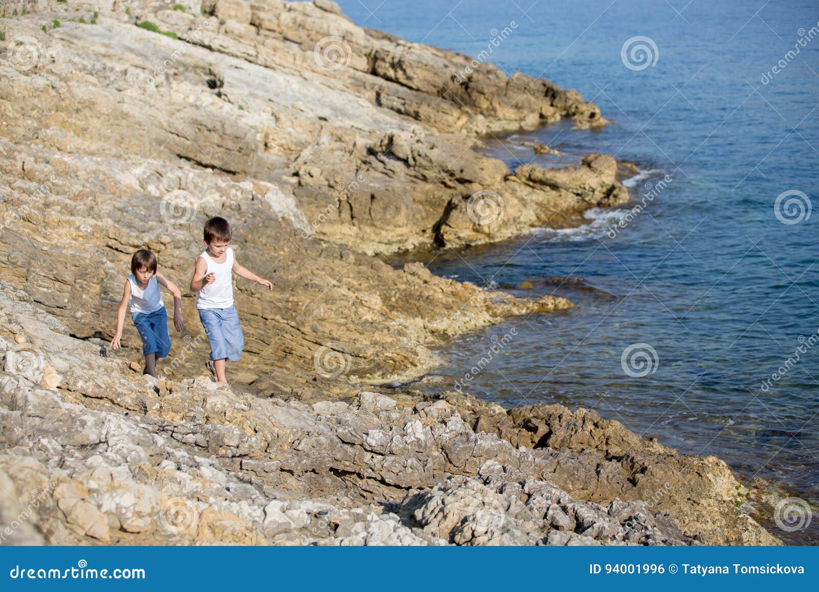 Two Children, Boys, Running on Rocks on the Shore of the Sea Stock ...