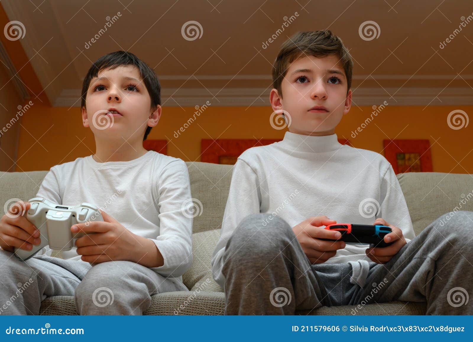 Two Children with Console Controls on a Sofa Stock Photo - Image of ...