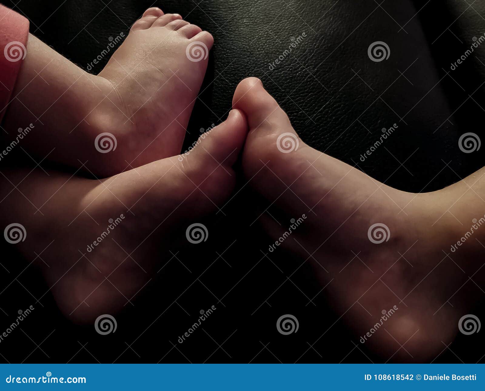 Two Children Feet Touching on Black Sofa Stock Photo - Image of cover ...