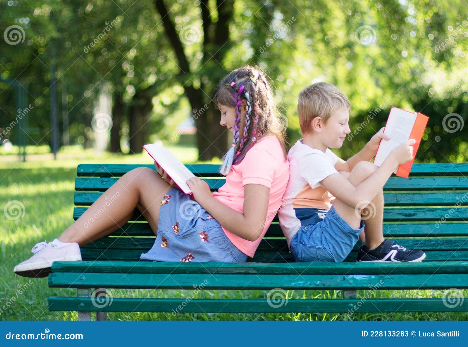 Two Children Sit on the Bench Back To Back are Reading a Book at Park ...