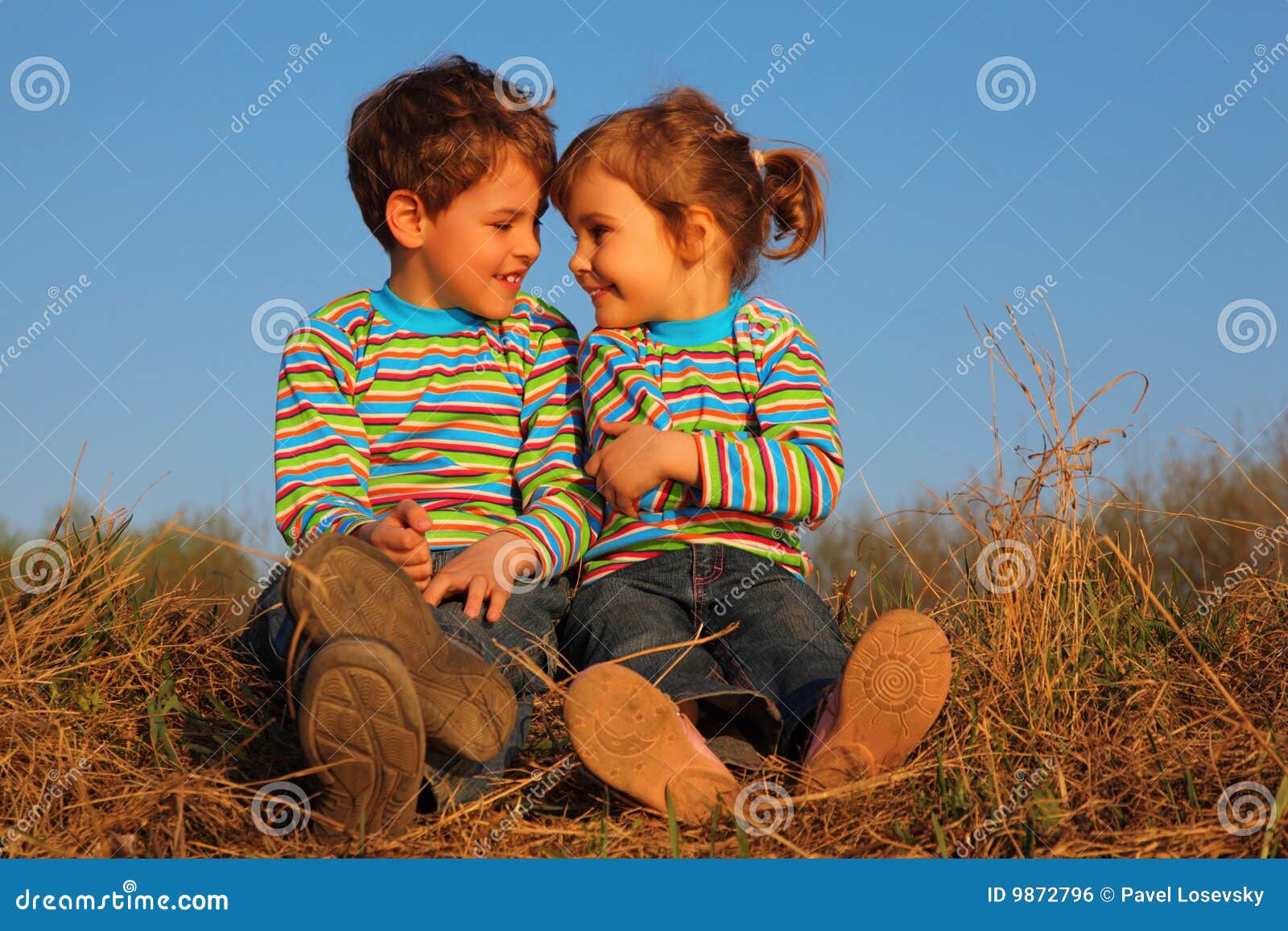 Two Children Sit on Dry Grass Stock Photo - Image of outside, dress ...