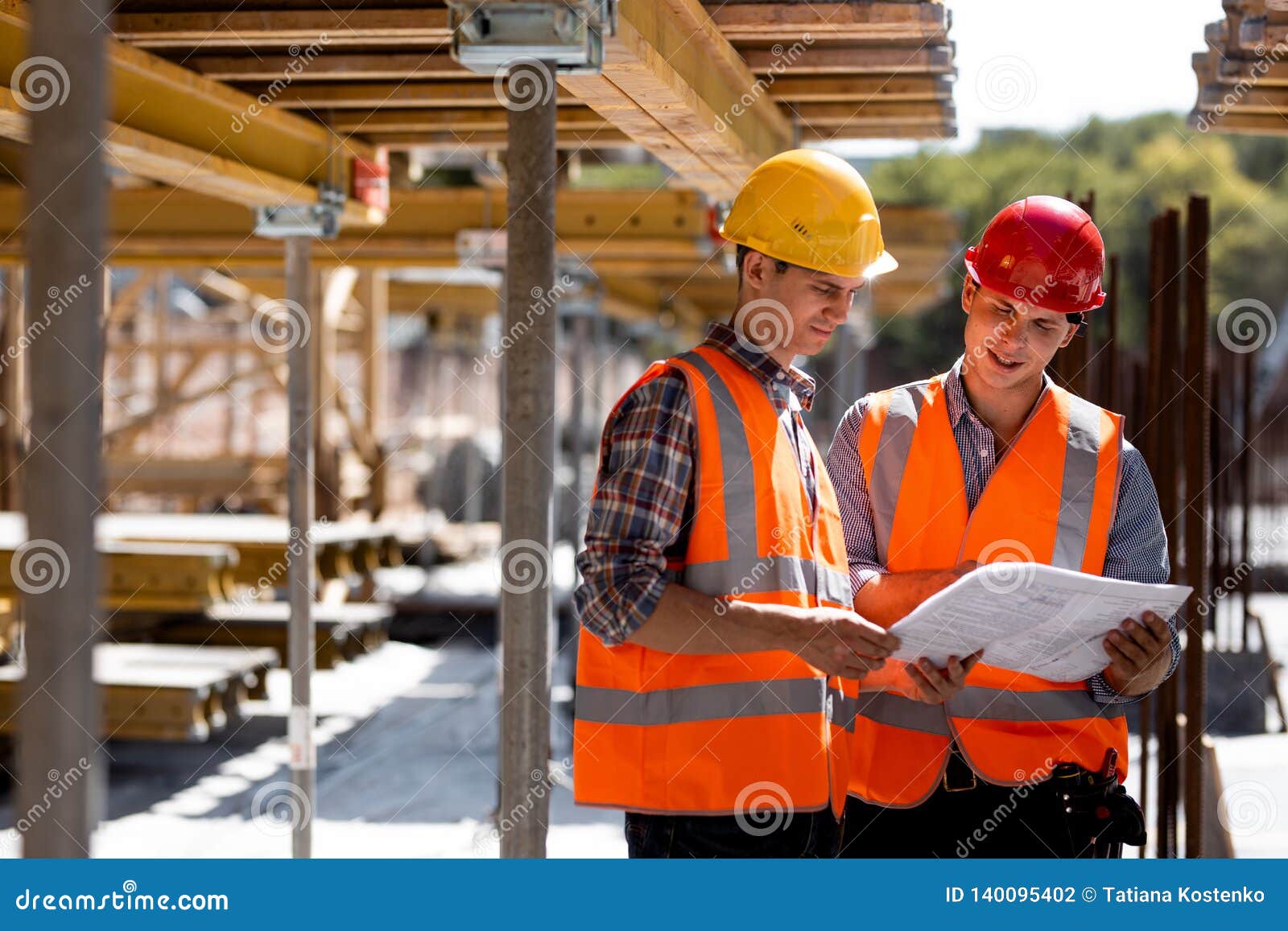 Two Civil Engineers Dressed in Orange Work Vests and Helmets Explore ...