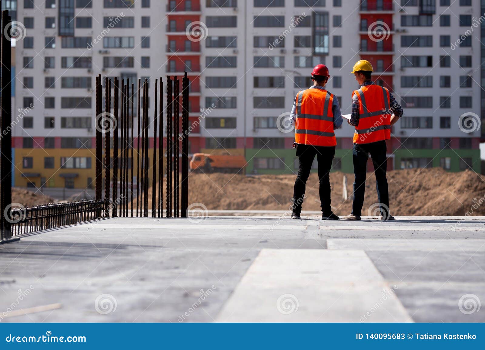 Two Civil Engineers Dressed in Orange Work Vests and Helmets Talk about ...