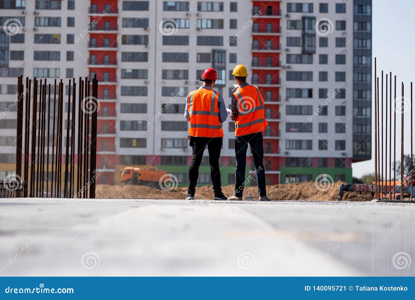 Two Civil Engineers Dressed in Orange Work Vests and Helmets Talk about ...