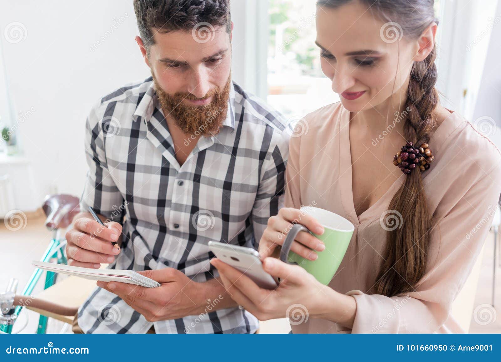 Two Co-workers Smiling while Watching a Video on the Mobile in a Stock ...
