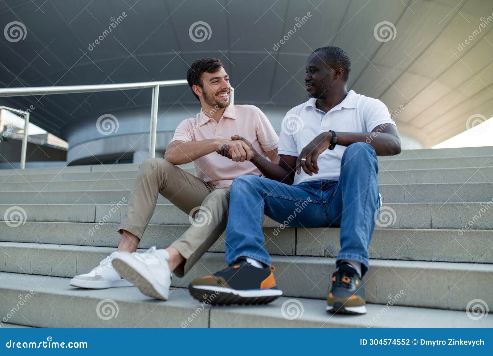 Two Colleagues Sitting Together on Steps and Talking Stock Photo ...