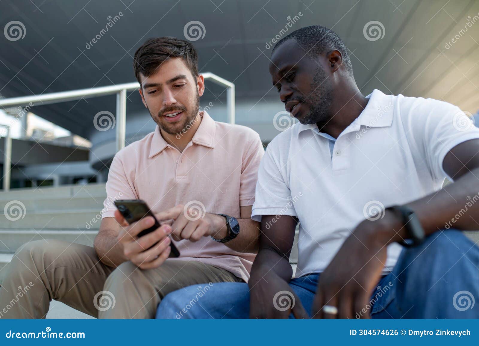 Two Colleagues Sitting Together on Steps and Talking Stock Photo ...