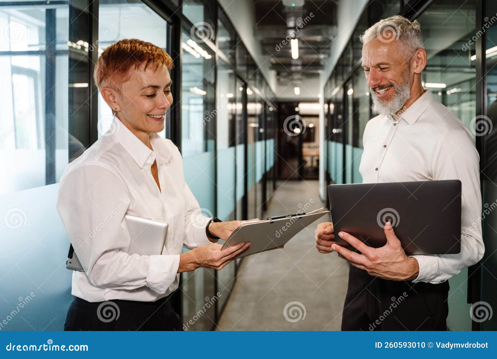 Two Colleagues Talking and Smiling while Working in Office Stock Photo ...