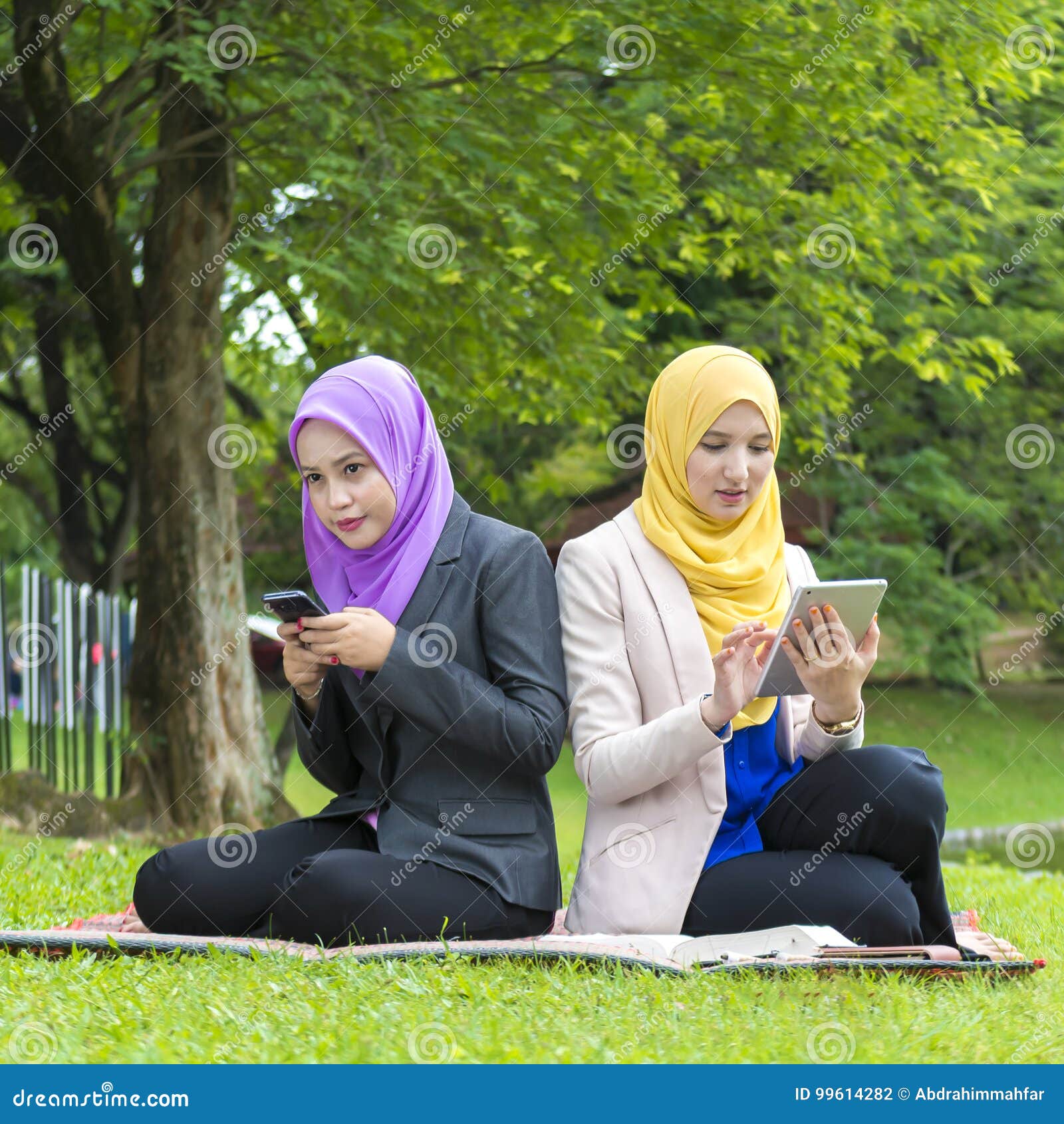 Two College Students Busy Texting with Their Smartphone while Resting ...