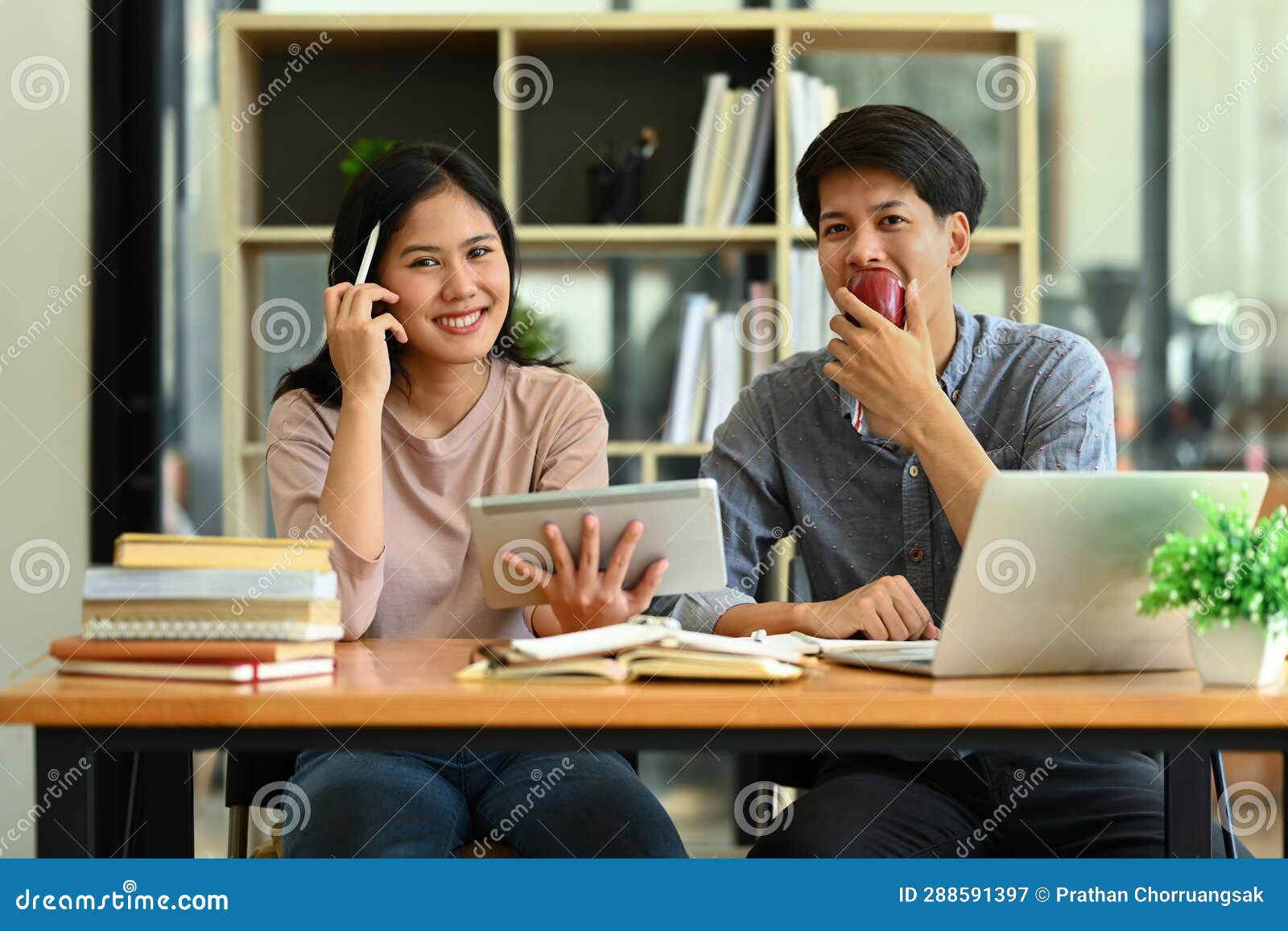 Two College Students Using Digital Tablet in Library, Studying Together ...