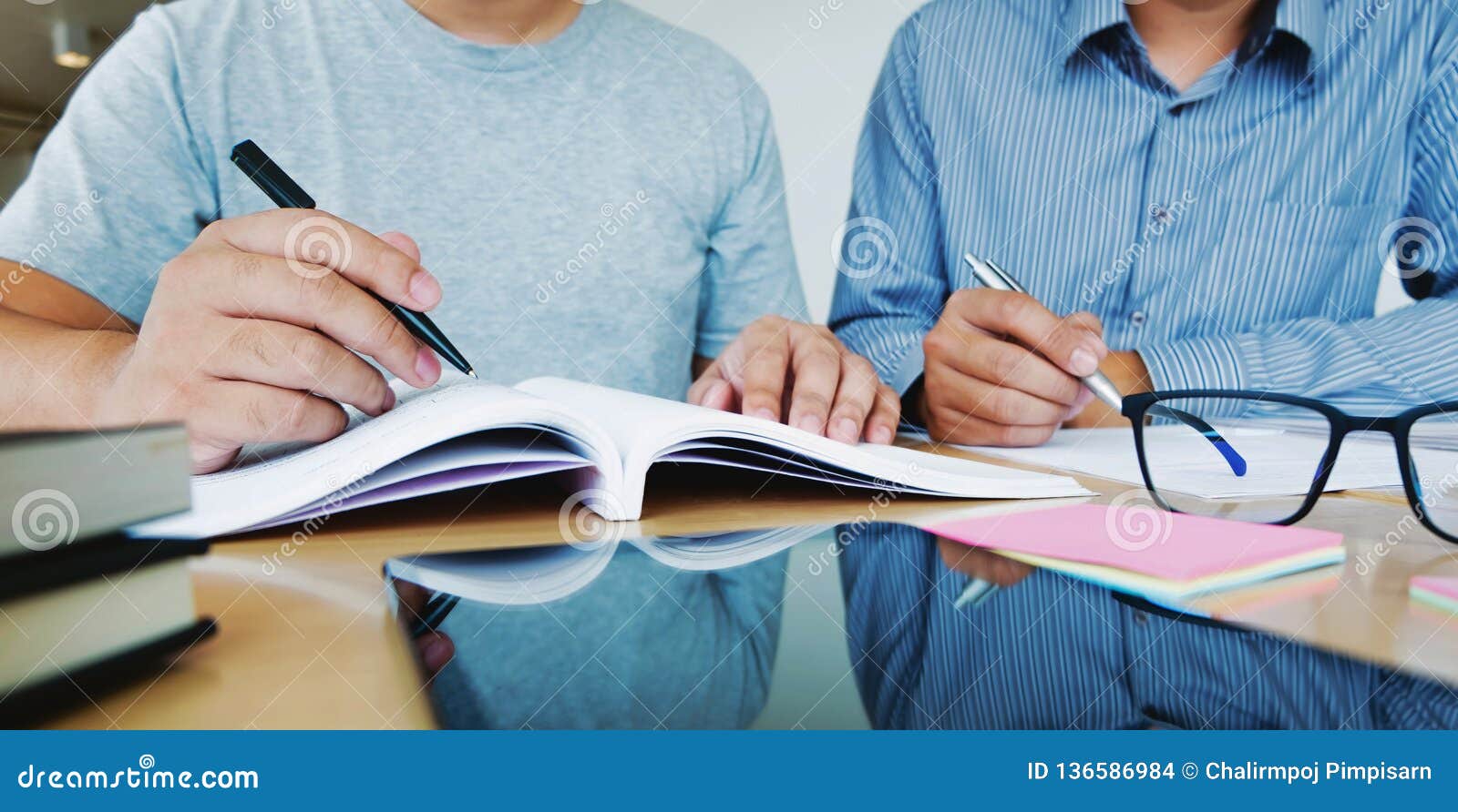 Two Confident Students Doing Homework Together while Sitting at the ...