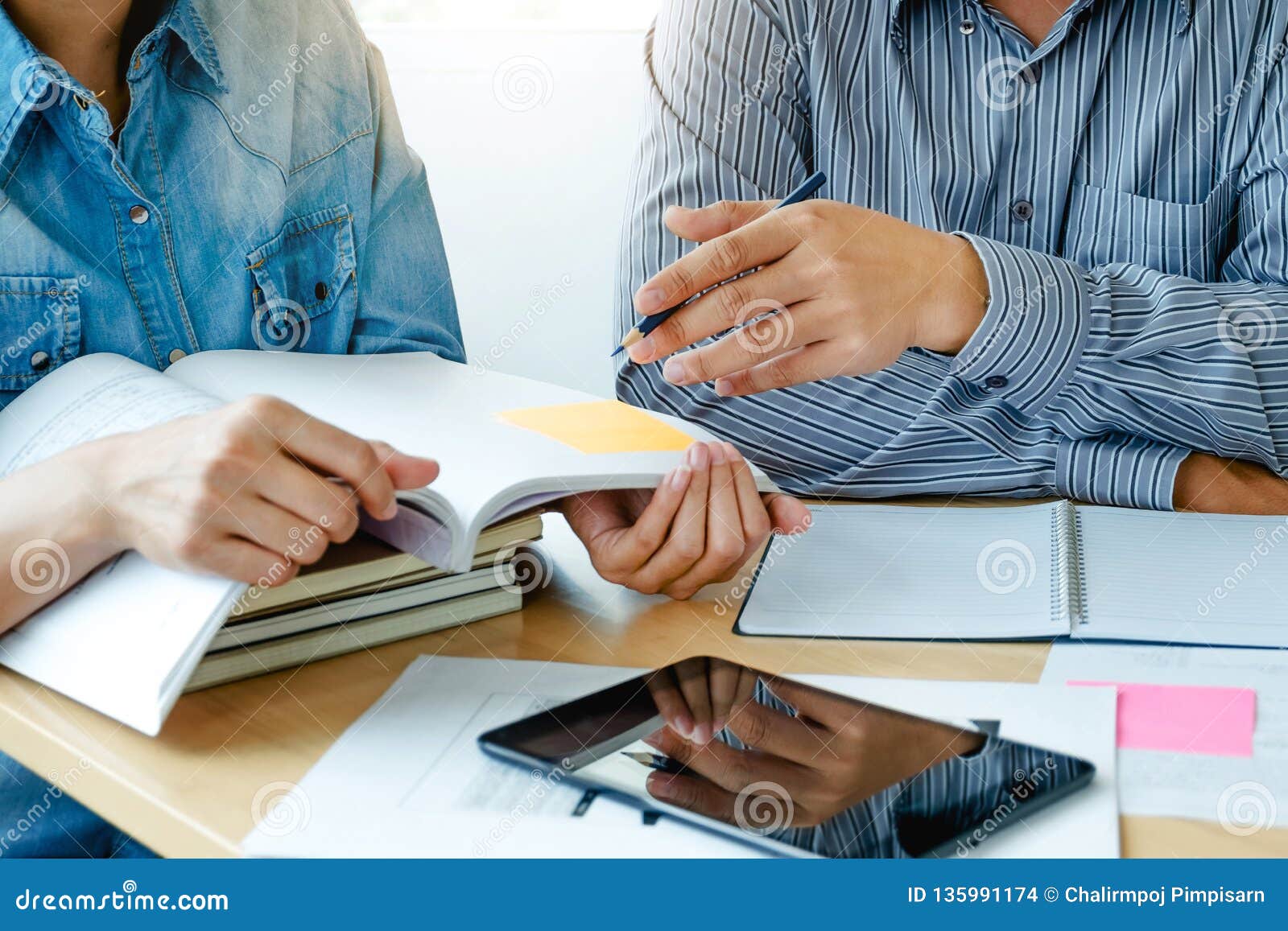 Two Confident Students Reading a Book or Doing Homework Together while ...