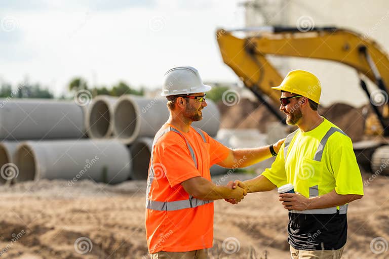 Two Construction Site Workers in Helmet Work Outdoors. Builders Workers Working on Construction ...