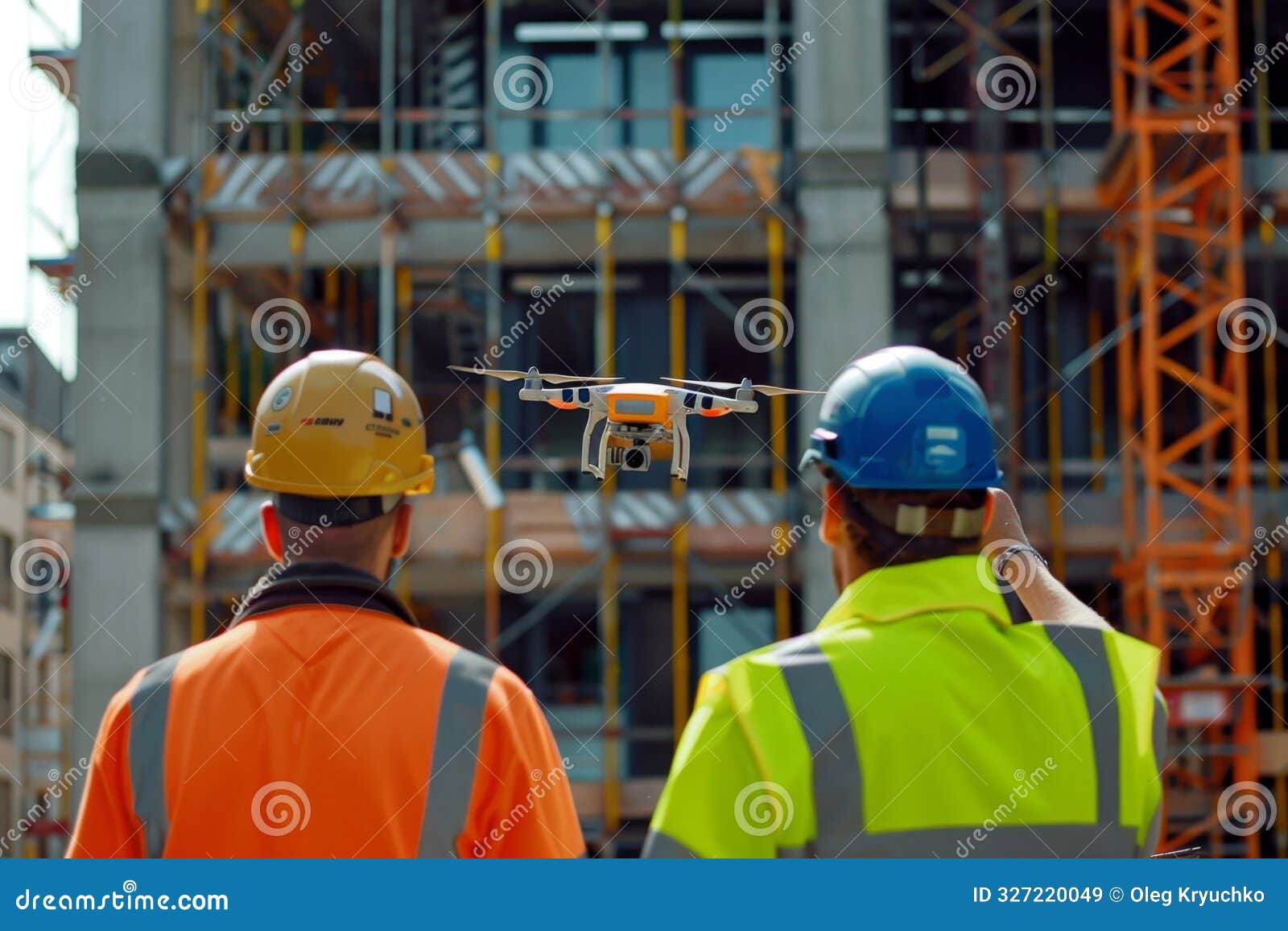 Two Construction Workers in Safety Gear Operate a Drone at a Building ...