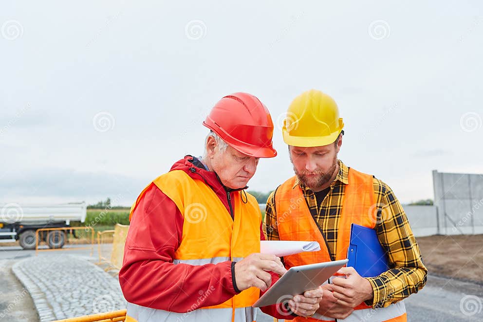 Two Construction Workers Using Tablet Computers on the Construction ...