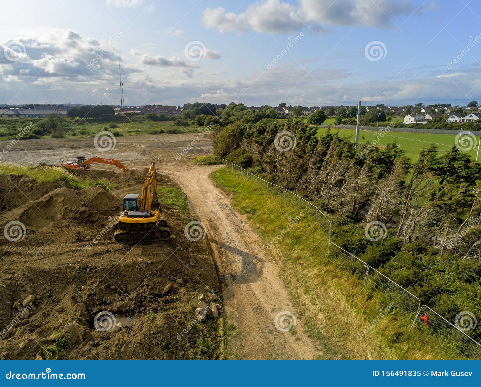Two Diggers at Work on a Construction Site, Sunny Day, Cloudy Sky ...