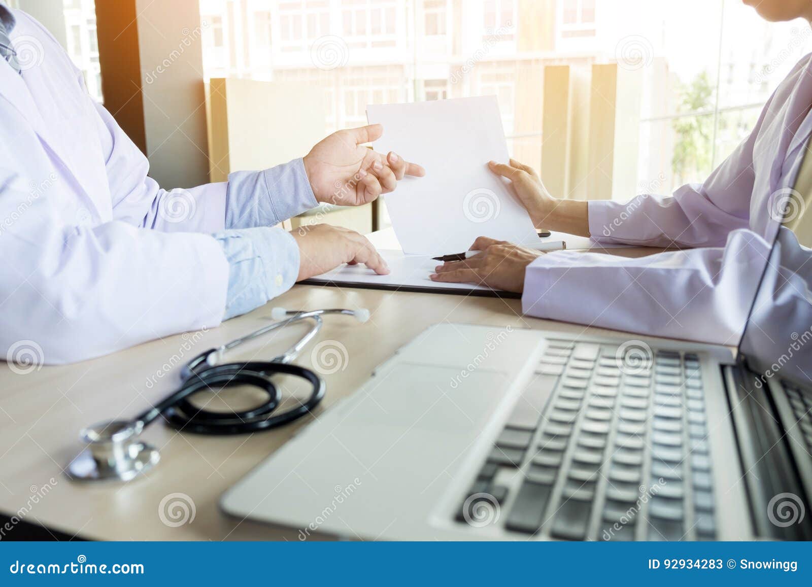 Two Doctors Discussing Patient Notes in an Office Pointing To a Stock ...