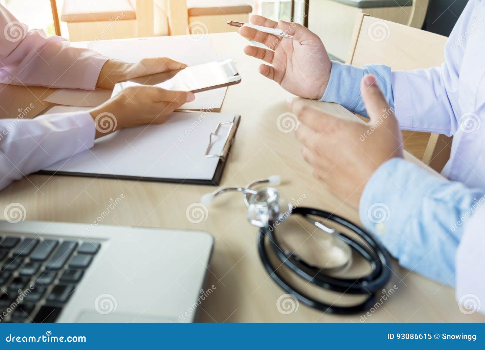 Two Doctors Discussing Patient Notes in an Office Pointing To a Stock ...