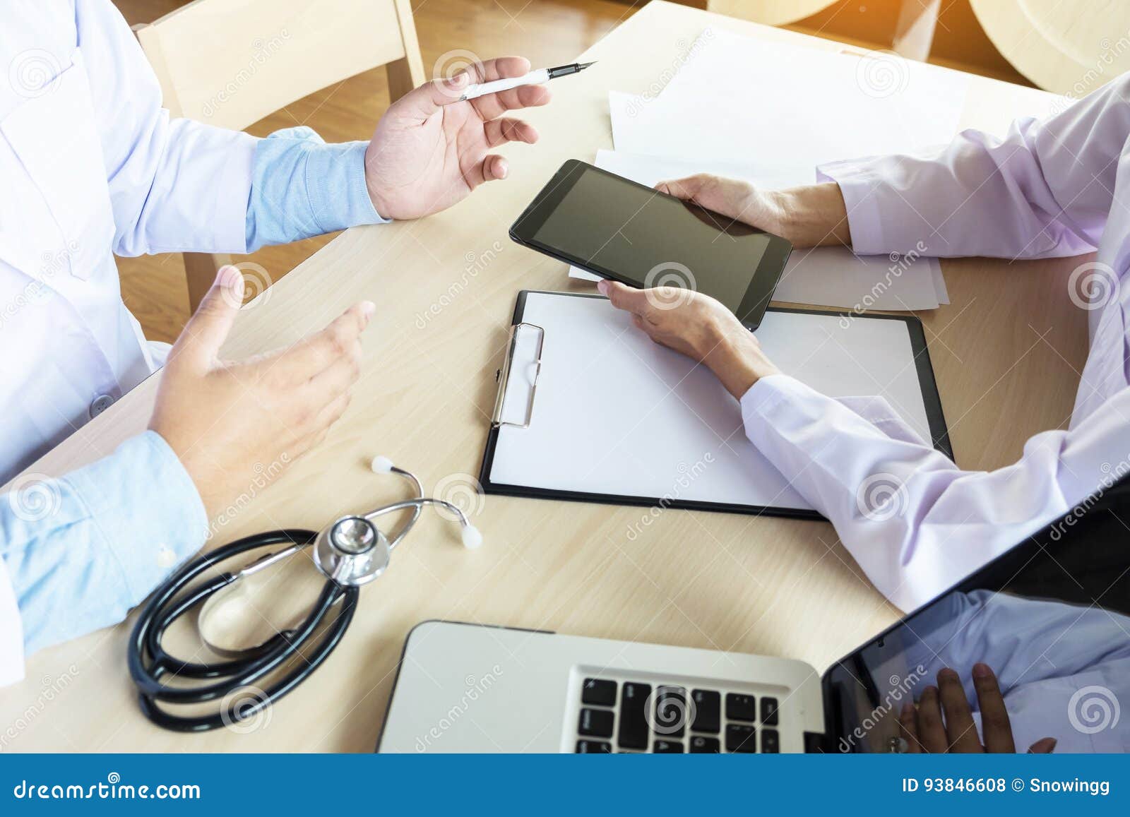 Two Doctors Discussing Patient Notes in an Office Pointing To a Stock ...