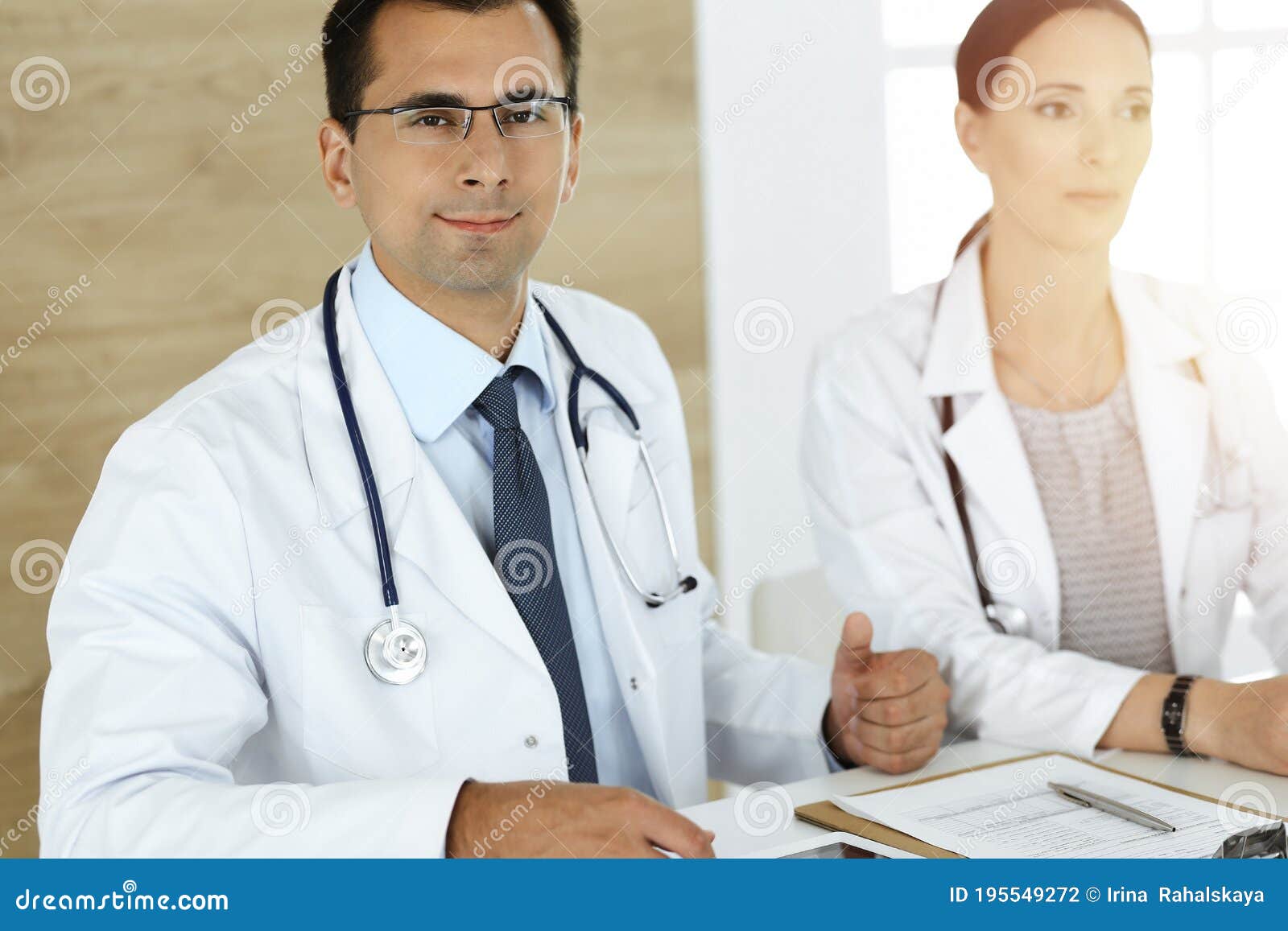 Two Doctors Discussing Treatment Problems while Sitting at the Desk in ...