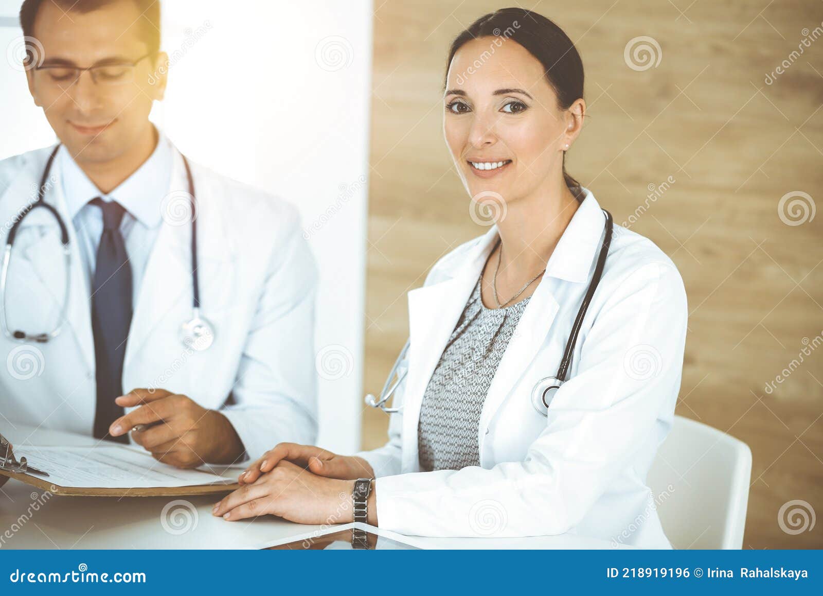 Two Doctors Discussing Treatment Problems while Sitting at the Desk in ...