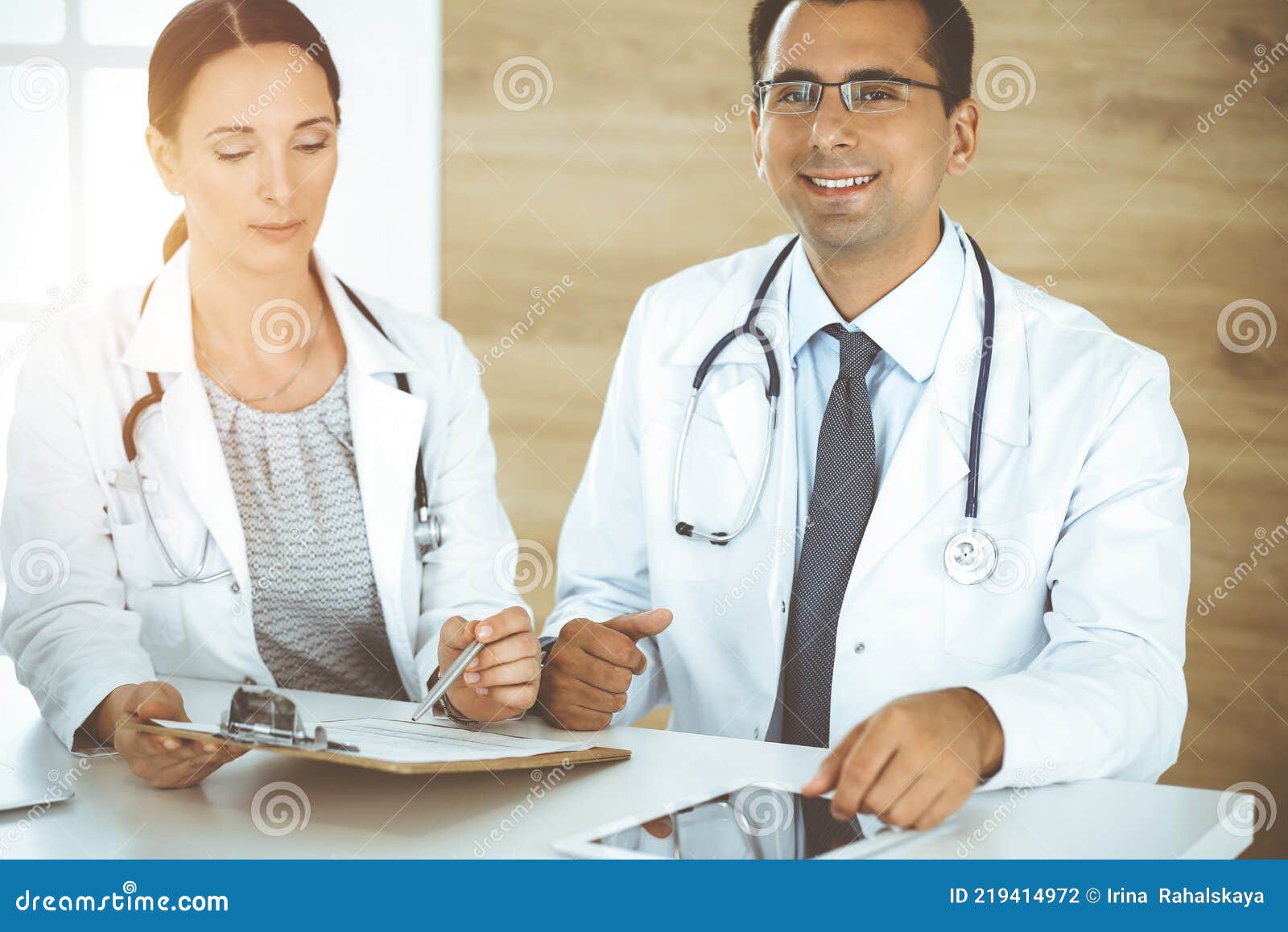 Two Doctors Discussing Treatment Problems while Sitting at the Desk in ...