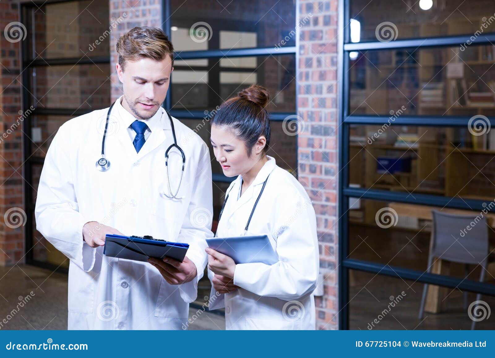 Two Doctors Looking at Clipboard and Discussing Near Library Stock ...