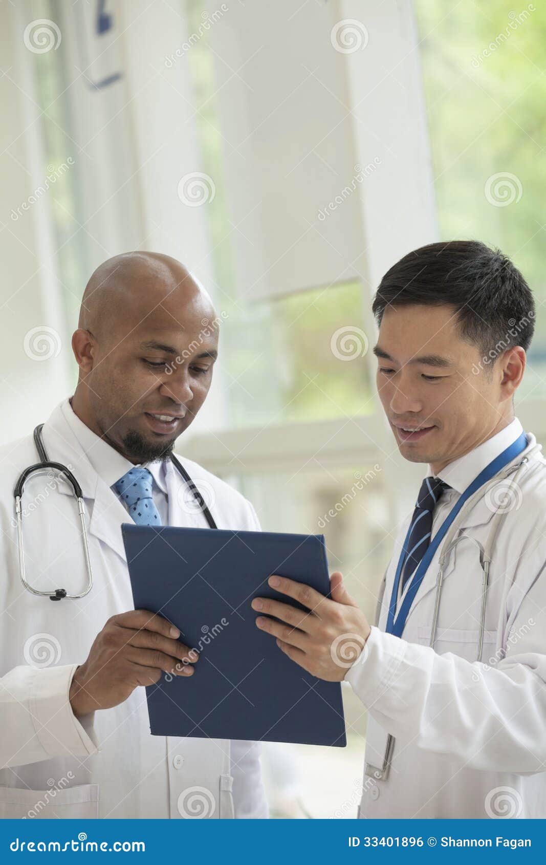 Two Doctors Looking Down and Consulting Over Medical Record in the ...