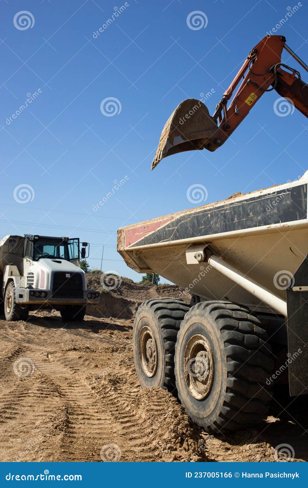 Two Dump Trucks and an Excavator Boom at a Construction Site Stock ...