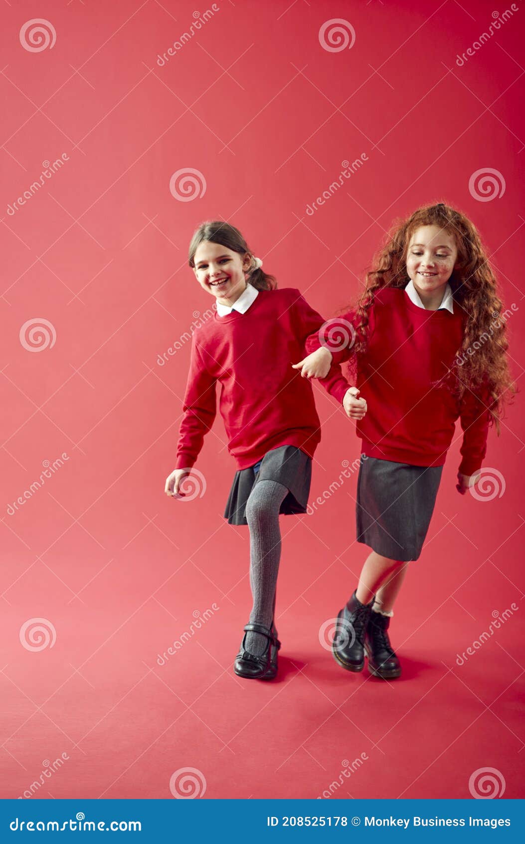 Two Elementary School Pupils Wearing Uniform Linking Arms Against Red ...