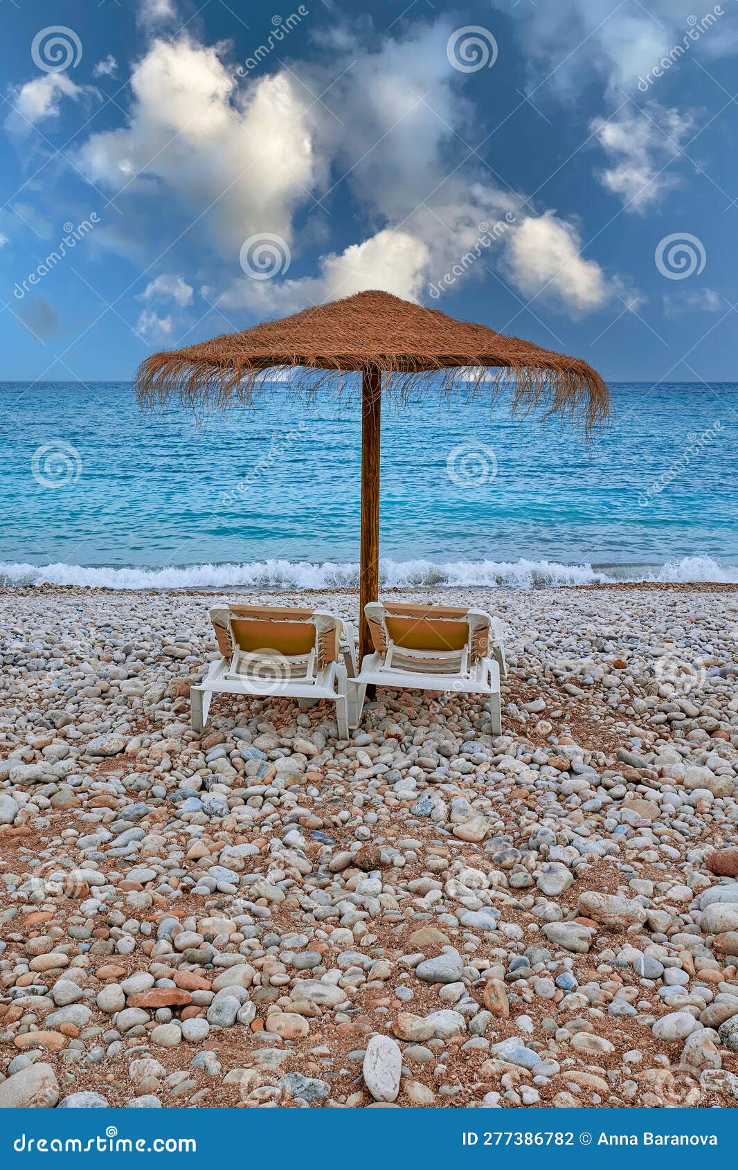 Empty Sun Loungers Under an Umbrella on a Pebble Beach by the Sea Stock ...