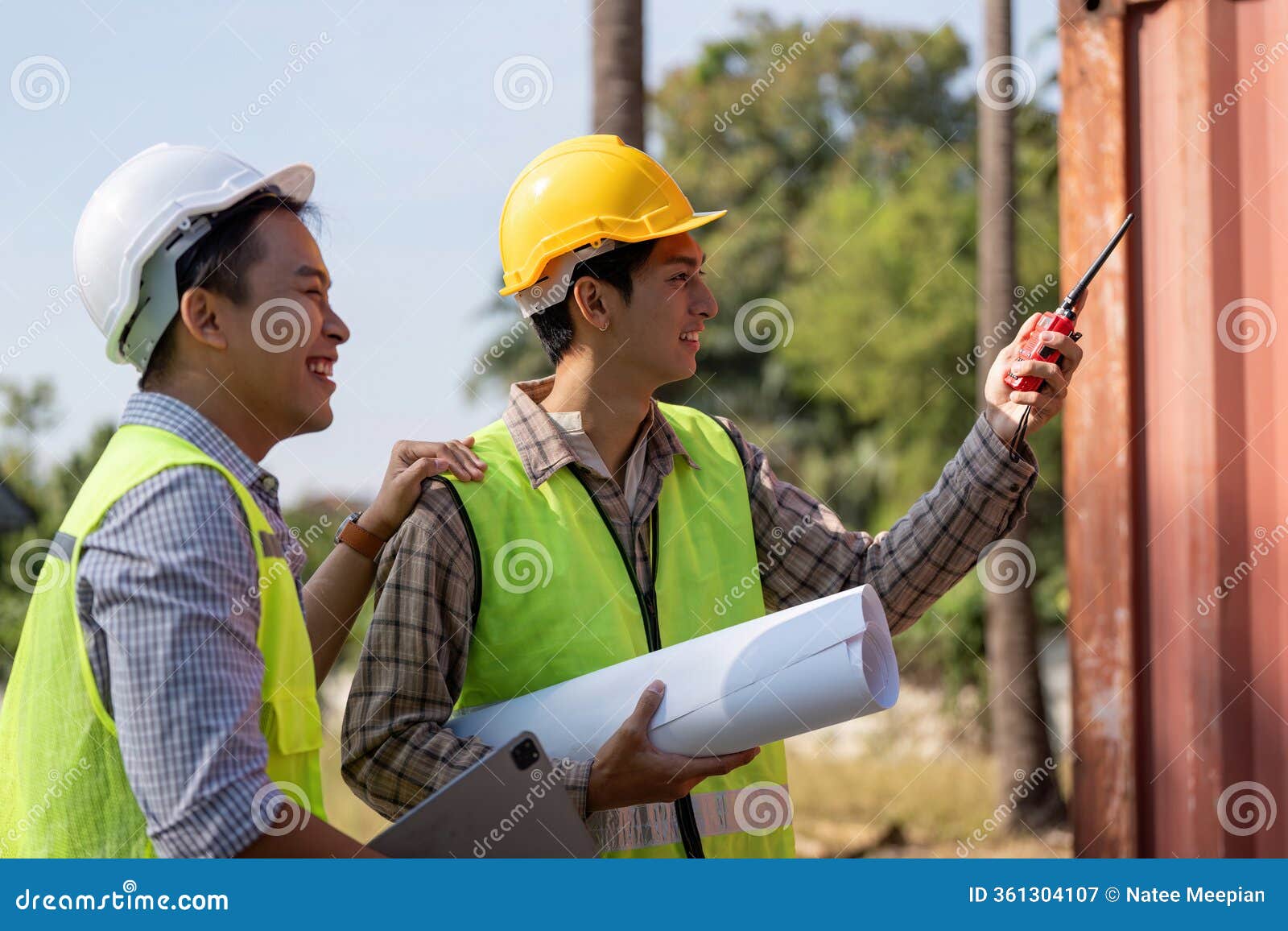 Engineers Collaborating on Construction Plans Outdoors with Blueprints ...