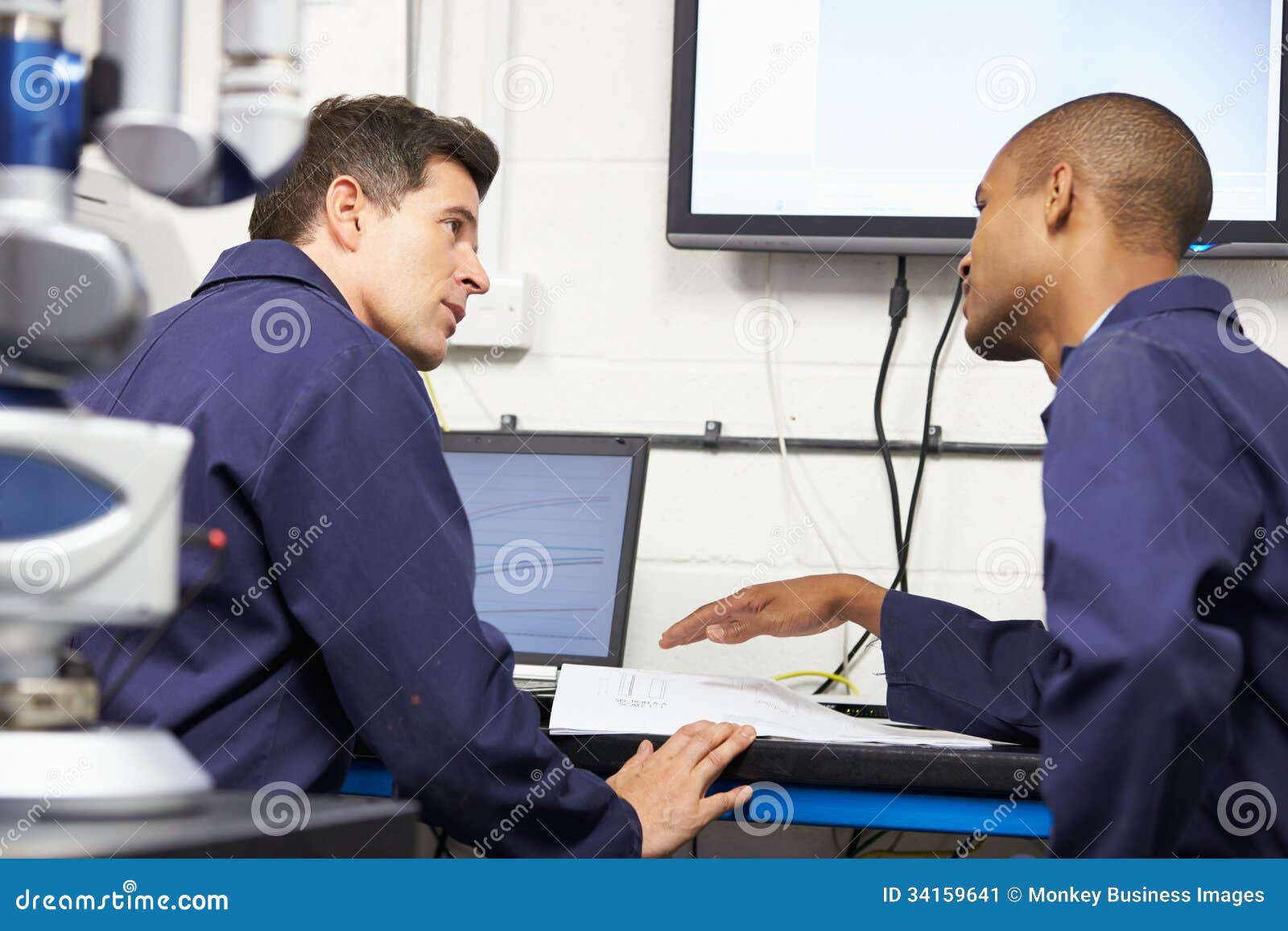Two Engineers Discussing Plans with CMM Arm in Foreground Stock Image ...