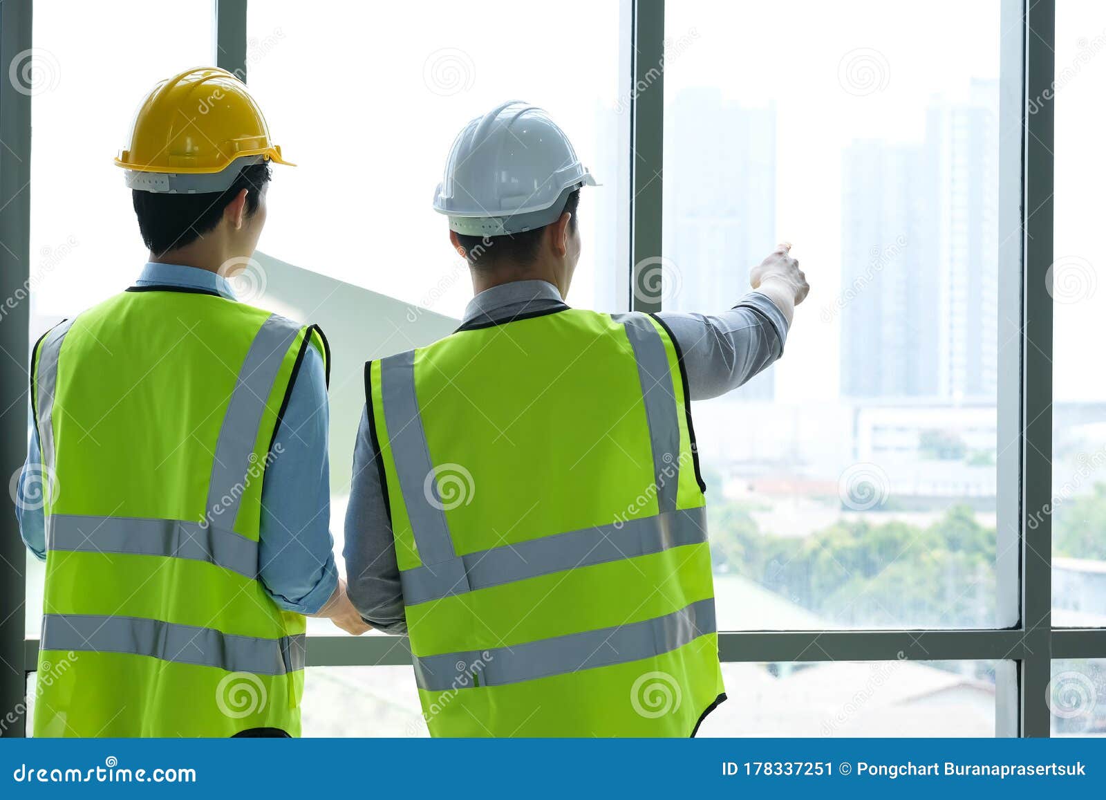 Two Engineers Man Standing in Front of Windows. Left Engineer Holding ...