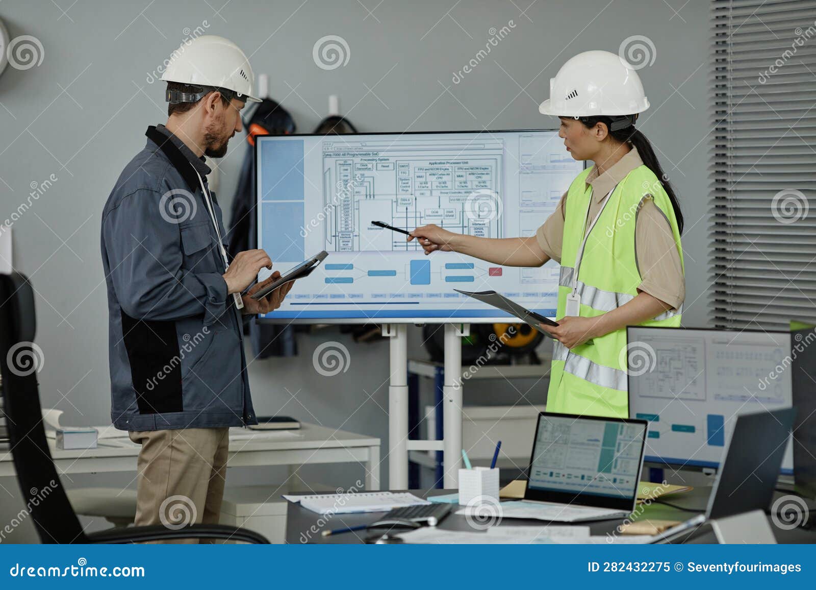 Two Engineers Reviewing Blueprints Indoors and Pointing at Computer ...