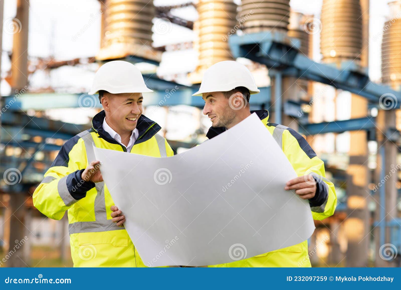 Two Engineers are Talking in Front of Electrical Transmission Lines ...