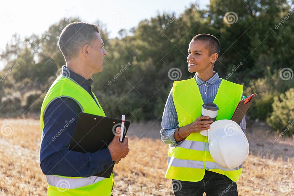 Two Engineers Talking while Working Together Outdoors in the Field ...