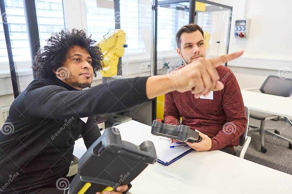 Two Engineers Training in Robotics Using Gripper Arm Controllers in a Modern Industrial Setting ...