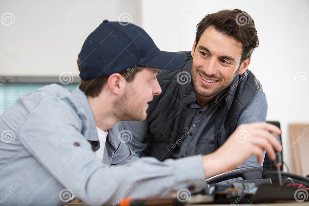 Two Experts Talking at Work Station Stock Photo - Image of headwear ...