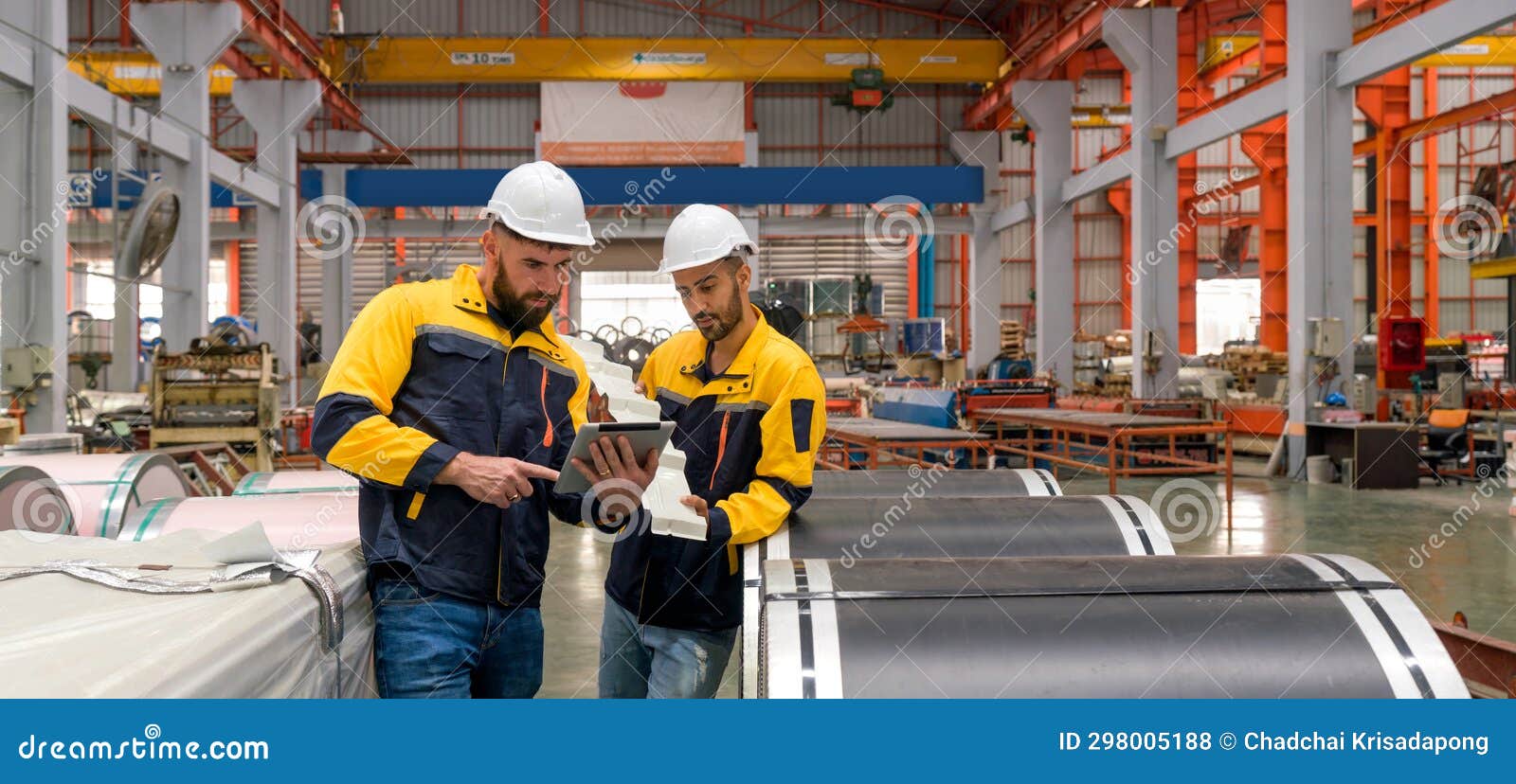 Two Factory Workers are Inspecting a Stack of Large Steel Coils in an ...