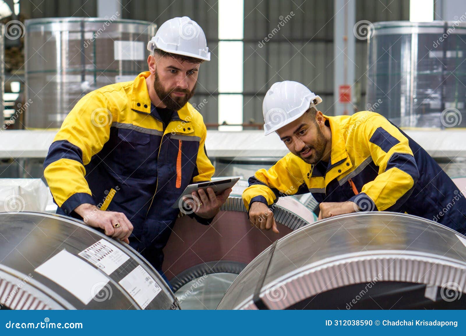 Two Factory Workers are Inspecting a Stack of Large Steel Coils in an ...