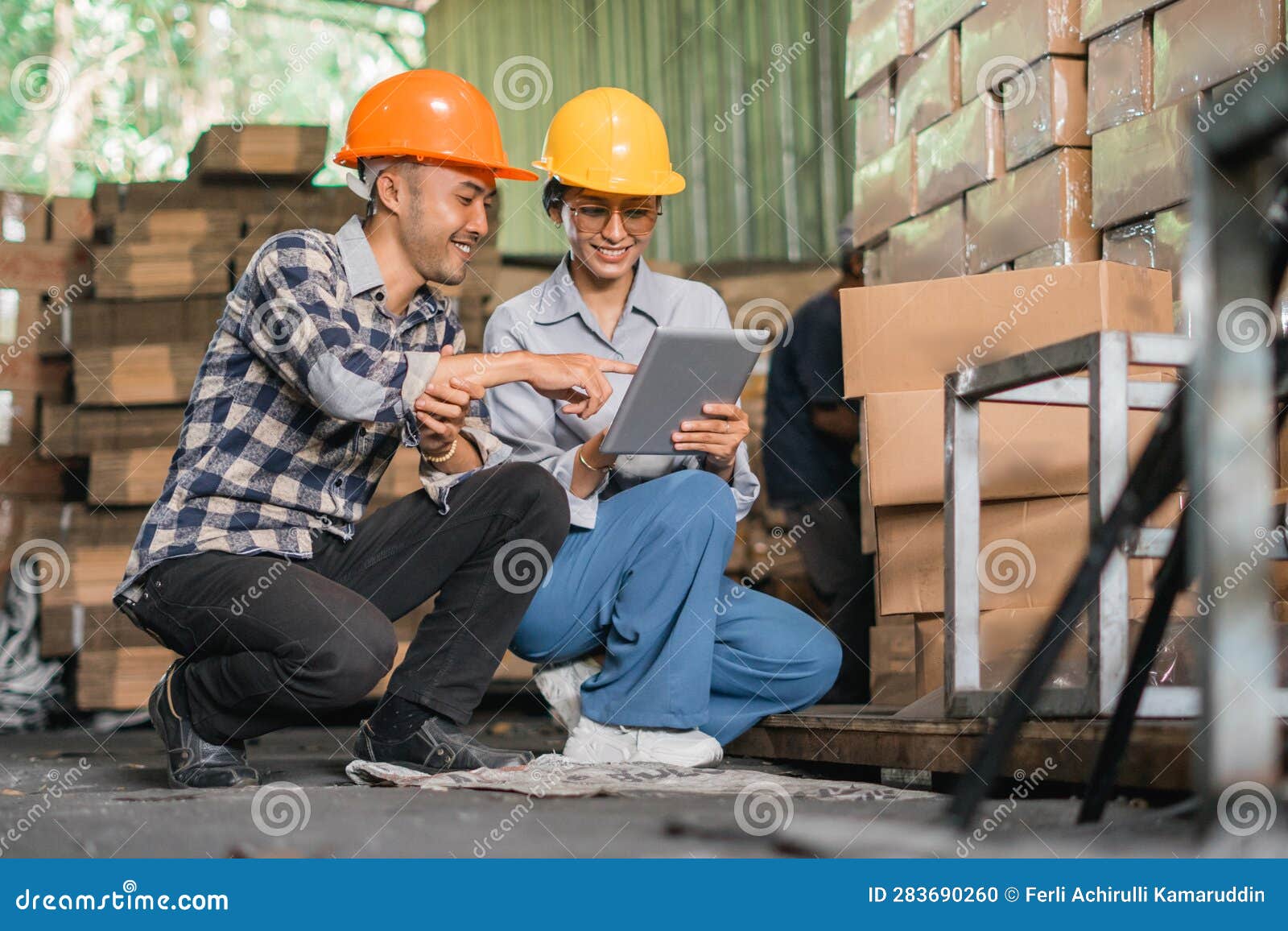 Two Factory Workers Wear Safety Helmets while Squatting Using a Tablet ...