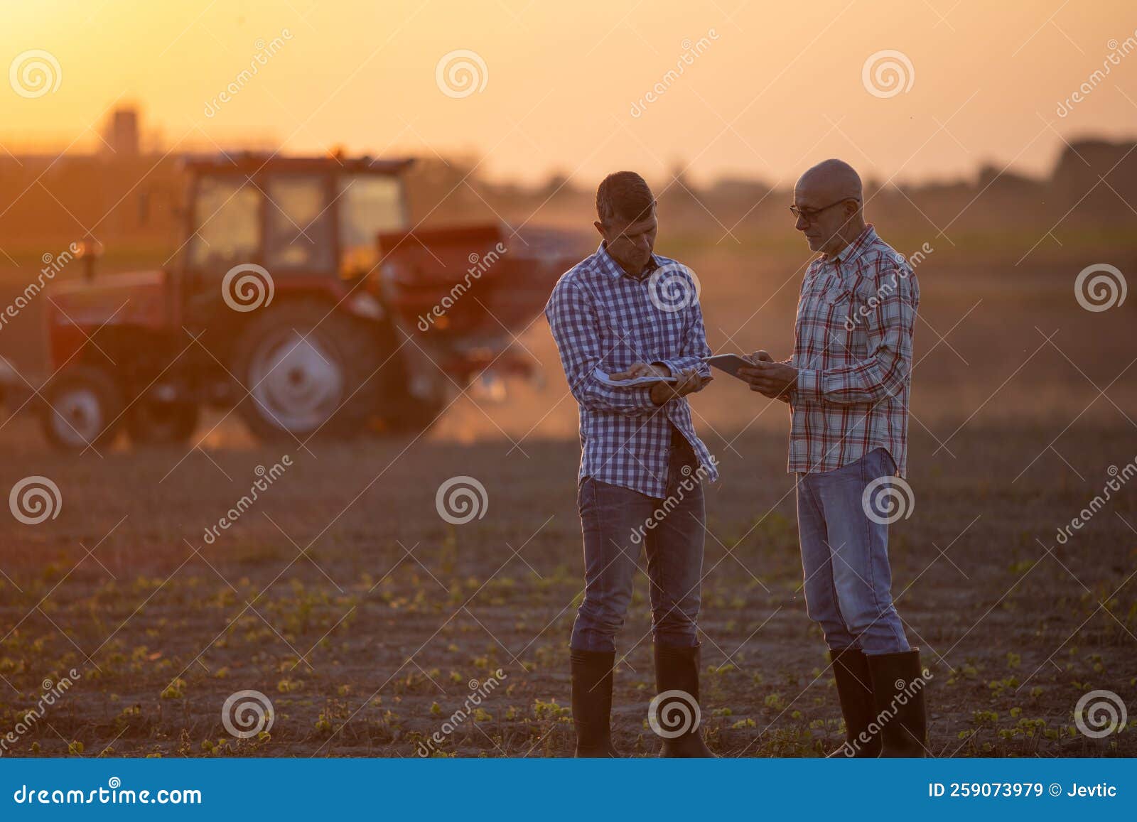 Two Farmers in Field with Tractor in Background Stock Image - Image of ...